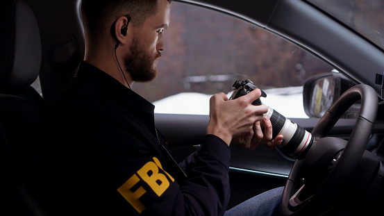 Young Handsome Fbi Agent With A Camera On A Drivers Seat In A Car An