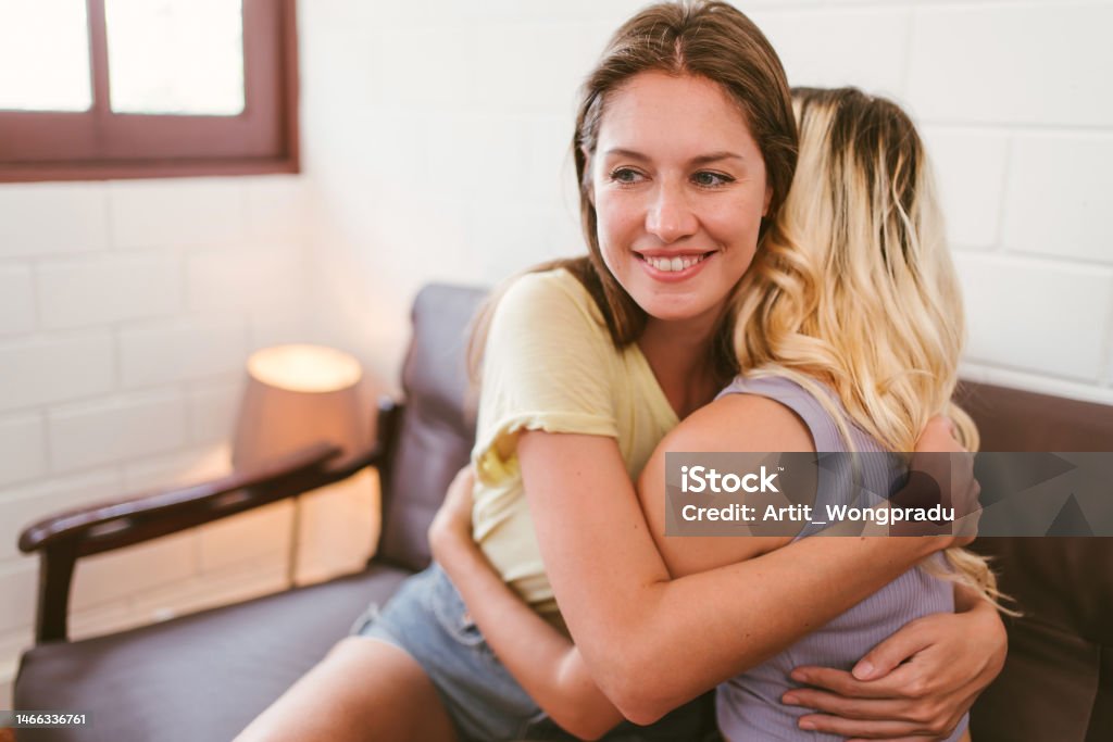 Happy Caucasian Lesbian Couple Cuddling Each Other With A Smile And