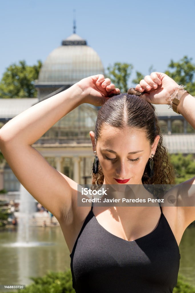 Woman Putting Her Hair Up In A Black Dress With A Glass And Metal