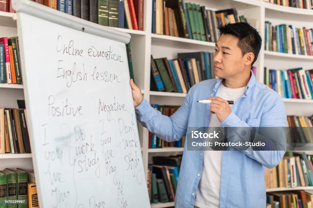 Chinese Teacher Man Teaching Writing On Whiteboard In Modern Classroom