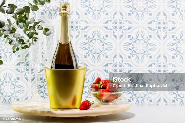 Botol Sampanye Dan Stroberi Segar Dalam Mangkuk Kaca Di Podium Kayu