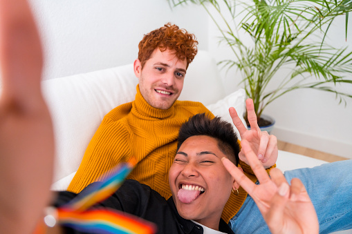Beautiful Gay Couple Being Romantic Indoors At Home On The Sofa Gay Couple Taking Selfie And