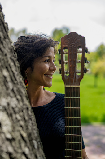 Portrait Of A Latina Woman Guitarist Smiling And Holding A Guitar In