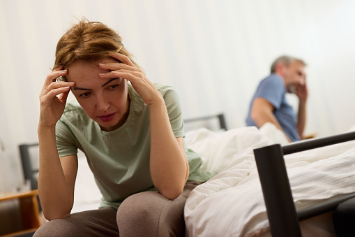 Couple Sitting On Different Sides Of Bed Not Talking After Argument
