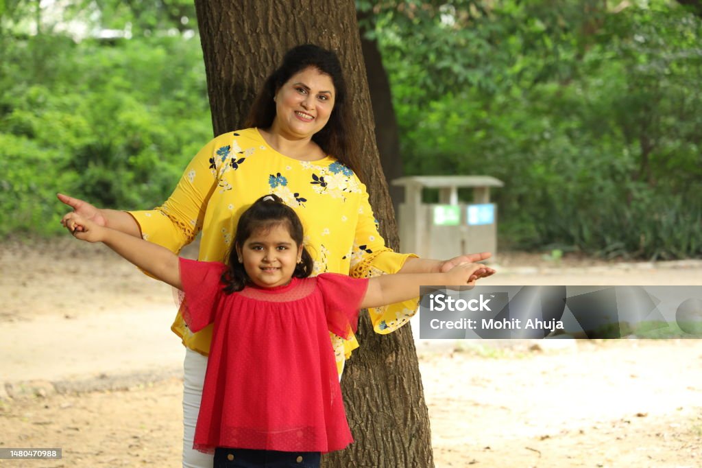 Happy Indian Mother And Daughter Enjoying Standing In Front Of A Tree