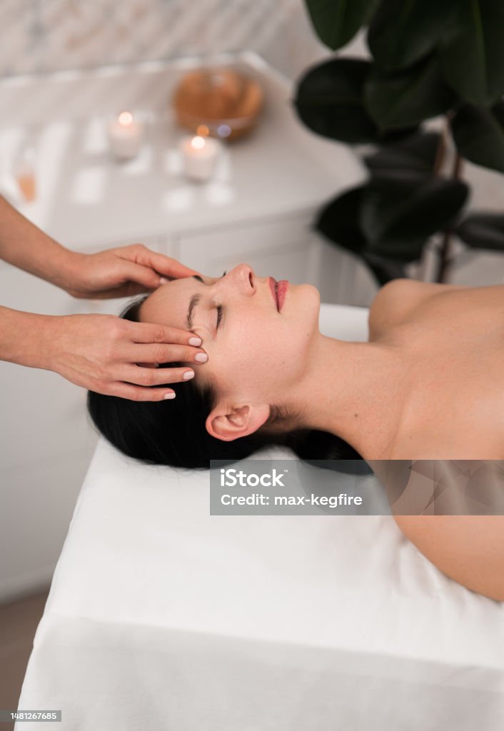 Crop Female Master Massaging Face Of Customer During Beauty Procedure