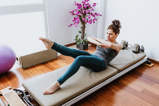 Mujer Latina Haciendo Ejercicios De Pilates En Cama Reformadora En Casa