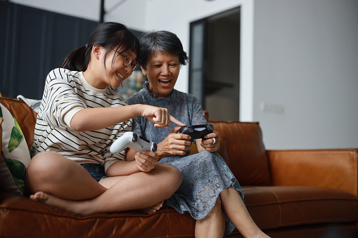Seorang Nenek Asia Yang Ceria Dan Cucunya Sedang Duduk Di Sofa Di Ruang ... Seorang Nenek Asia Yang Ceria Dan Cucunya Sedang Duduk Di Sofa Di Ruang ...