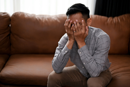 Stressed And Depressed Asian Man Is Covering His Face Crying On The