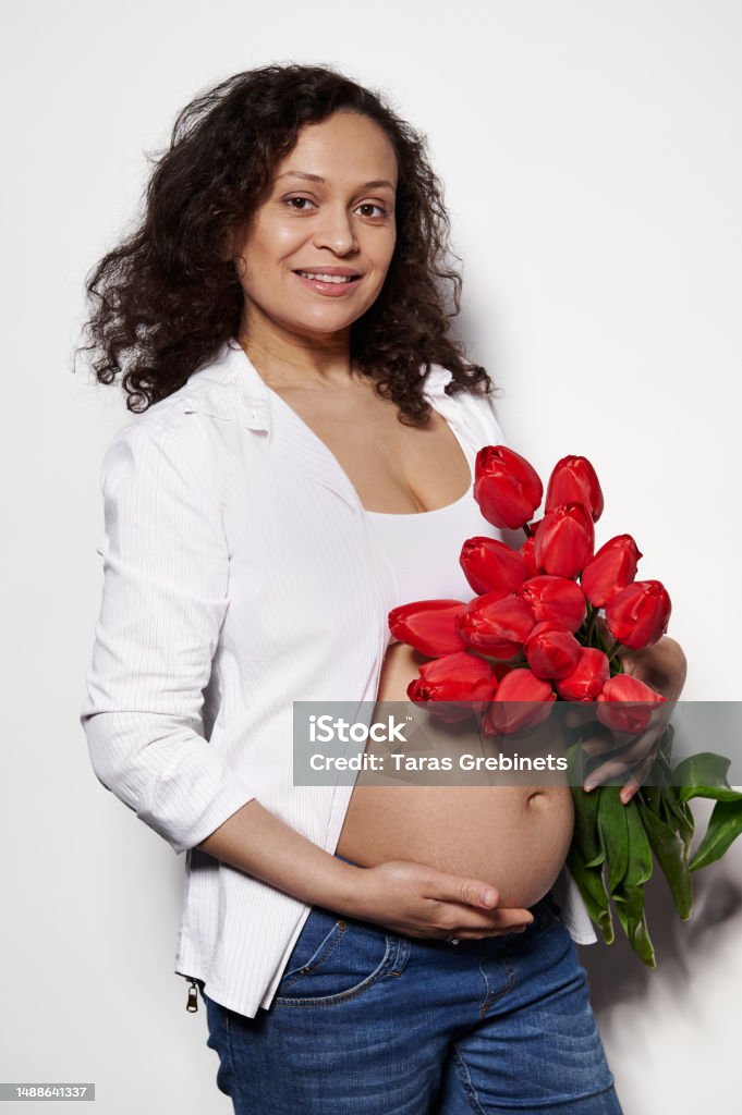 Multi Ethnic Pregnant Woman Posing Bare Belly With A Bouquet Of Red