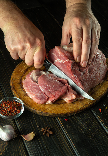 Koki Memotong Steak Daging Sapi Mentah Dengan Pisau Di Talenan Kayu