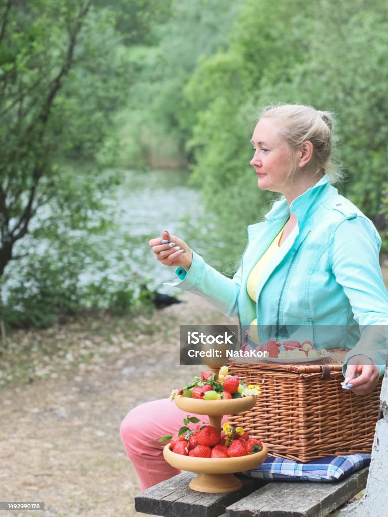 Blonde Woman In The Forest At A Picnic With Fruits In A Wooden Vase
