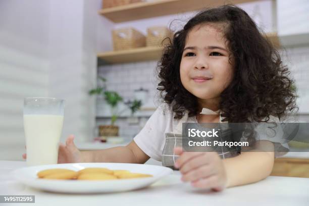 Young Hispanic Currly Hair Girl Sitting On Table And Drinking Milk