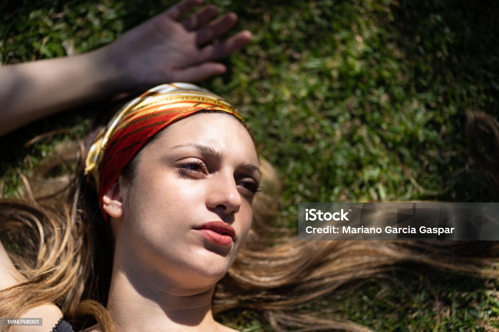 Overhead Portrait Of Blonde Woman Lying On The Grass With Lights And