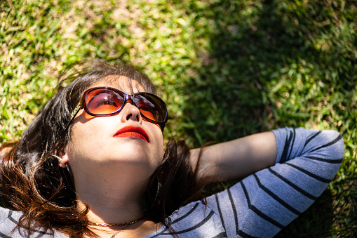 Overhead Portrait Of An Andean Woman With Sunglasses Lying On The Grass
