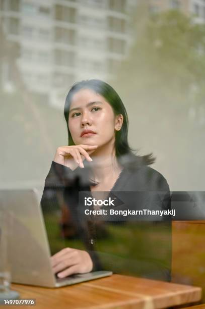 Seorang Pengusaha Wanita Asia Yang Serius Duduk Di Meja Dekat Jendela ... Seorang Pengusaha Wanita Asia Yang Serius Duduk Di Meja Dekat Jendela ...
