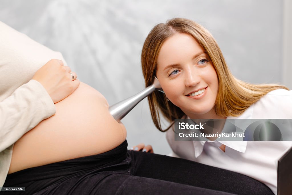 Photo Libre De Droit De Un Gynécologue Penche Un Stéthoscope Sur Le Ventre Dune Femme Enceinte