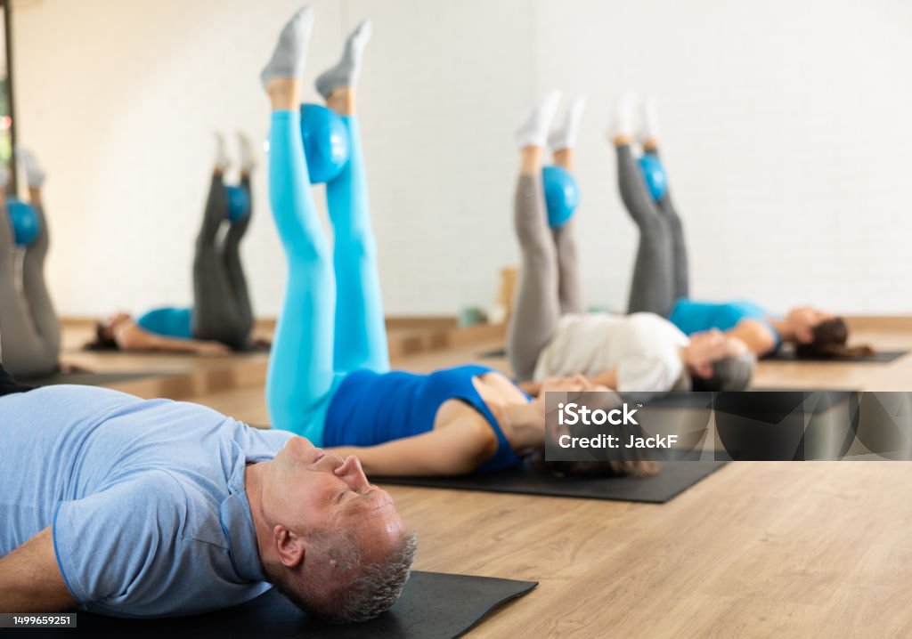 Class Of People Of Different Ages Holding Balls Between Legs And