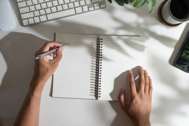 Free Stock Photo of Overhead view of hands writing on a notebook with ...