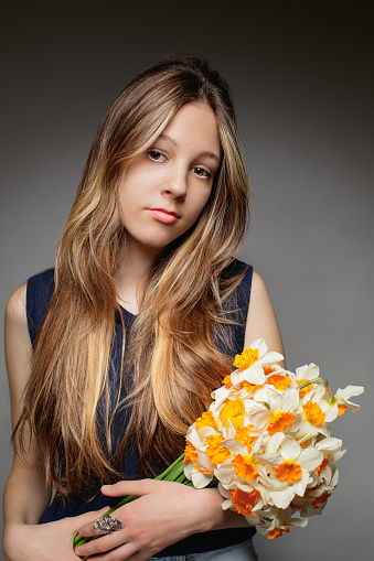 Naturally Blond Teenage Girl Holding Bunch Of Daffodils In Hands