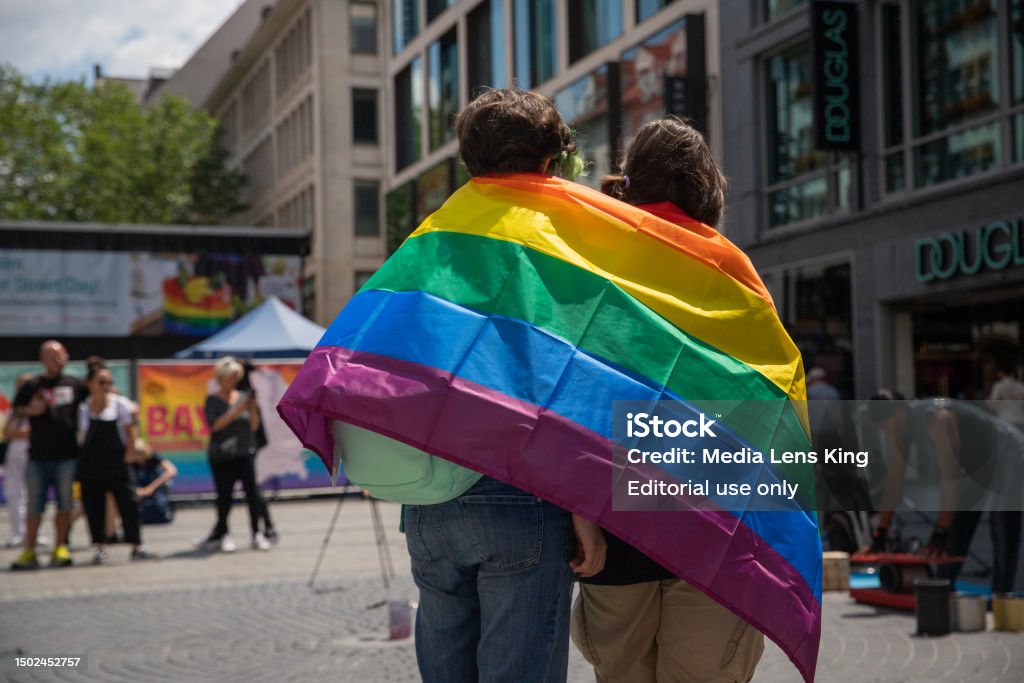 During The Gay Pride A Lesbian Couple Hug Each Other With A Rainbow