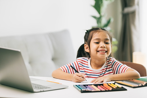 Gadis Asia Kecil Menggambar Dengan Pensil Warna Dan Laptop Di Rumah