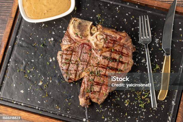 Tampilan Atas Tbone Steak Disajikan Di Atas Piring Batu Dengan Saus Di ... Tampilan Atas Tbone Steak Disajikan Di Atas Piring Batu Dengan Saus Di ...