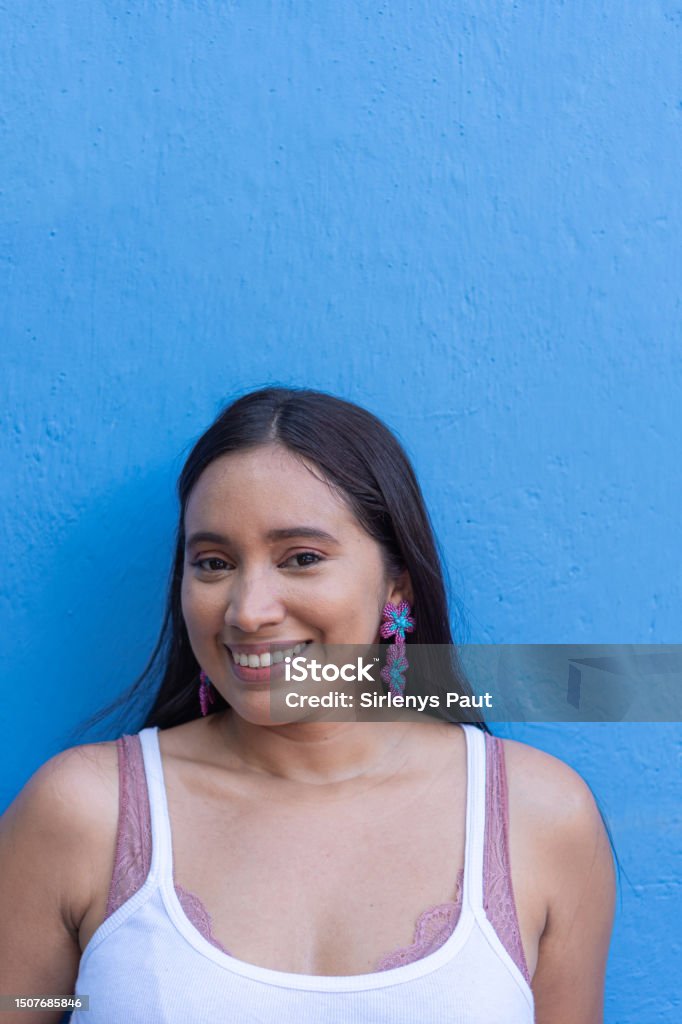 Portrait Of Latin Woman Standing And Leaning Against Wall In City