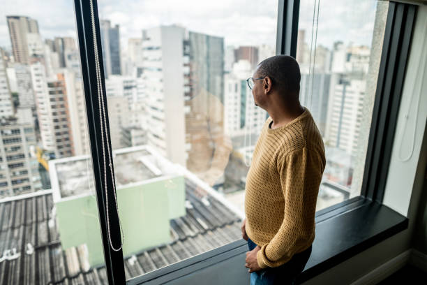 Free Stock Photo of Man Sitting on Window Sill Looking Out at City ...