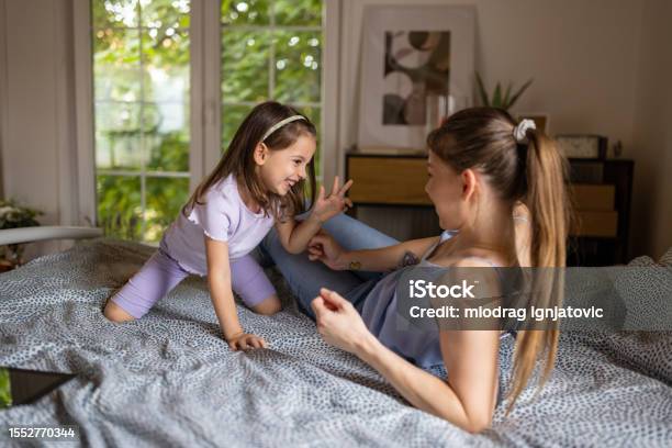 Mother And Daughter Playfully Tickling Each Other In The Bedroom Stock