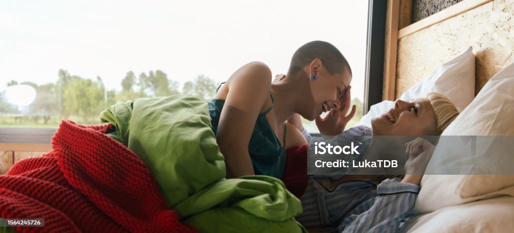 Two Cheerful Lesbian Women Hug Each Other While Lying In Bed After