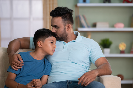 Ayah India Mencium Dahi Putranya Sambil Duduk Di Sofa Di Rumah Konsep
