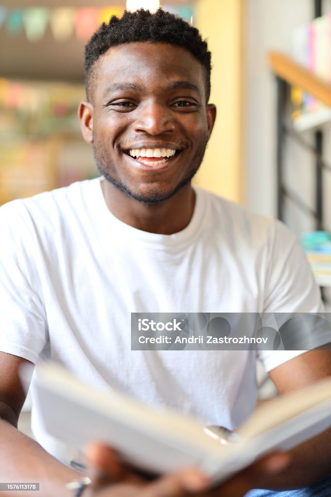 Handsome African American Man Wearing A White Tshirt And Holding A Book