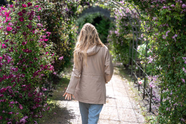 Free Stock Photo of Woman Walking Through Flower-Filled Garden ...