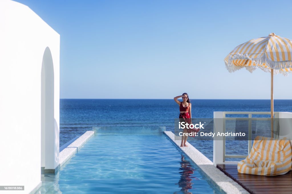 Beautiful Asian Woman Wearing Red Batik Cloth At Infinity Pool Side
