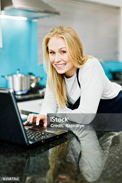 Koki Pirang Cantik Di Celemek Menggunakan Laptop Di Meja Dapur Foto