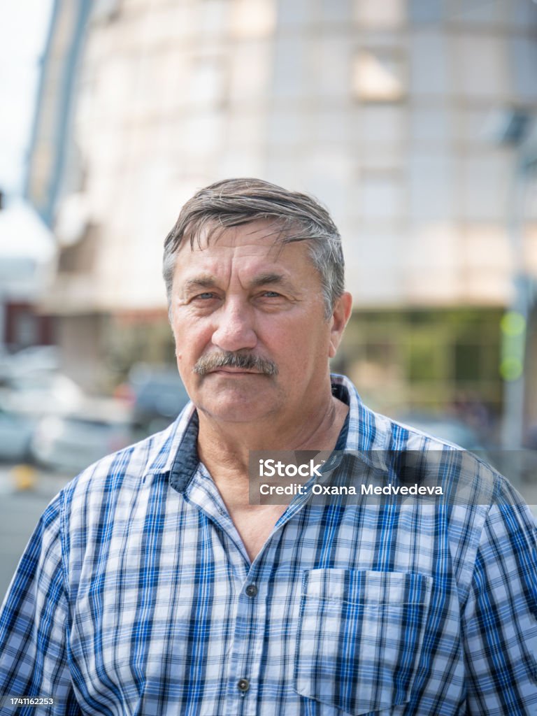 Grayhaired Elderly Man In Front Of A City Street A 70yearold Man Looks Seriously At The Camera