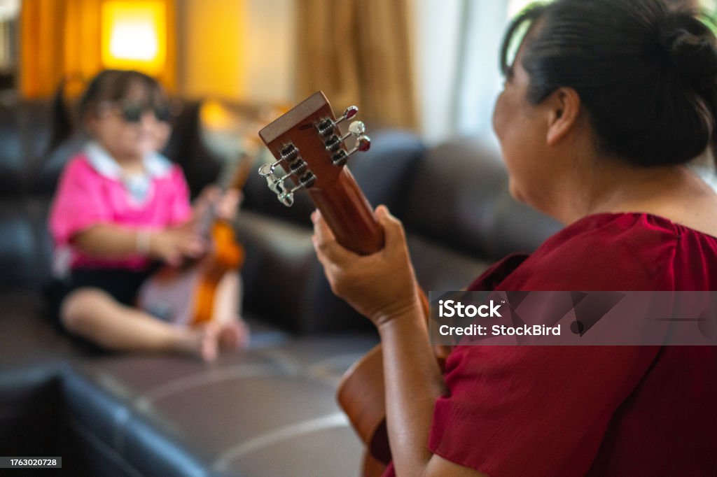 Asian Mother And Daughter Singing With Guitar And Ukulele At Home Stock
