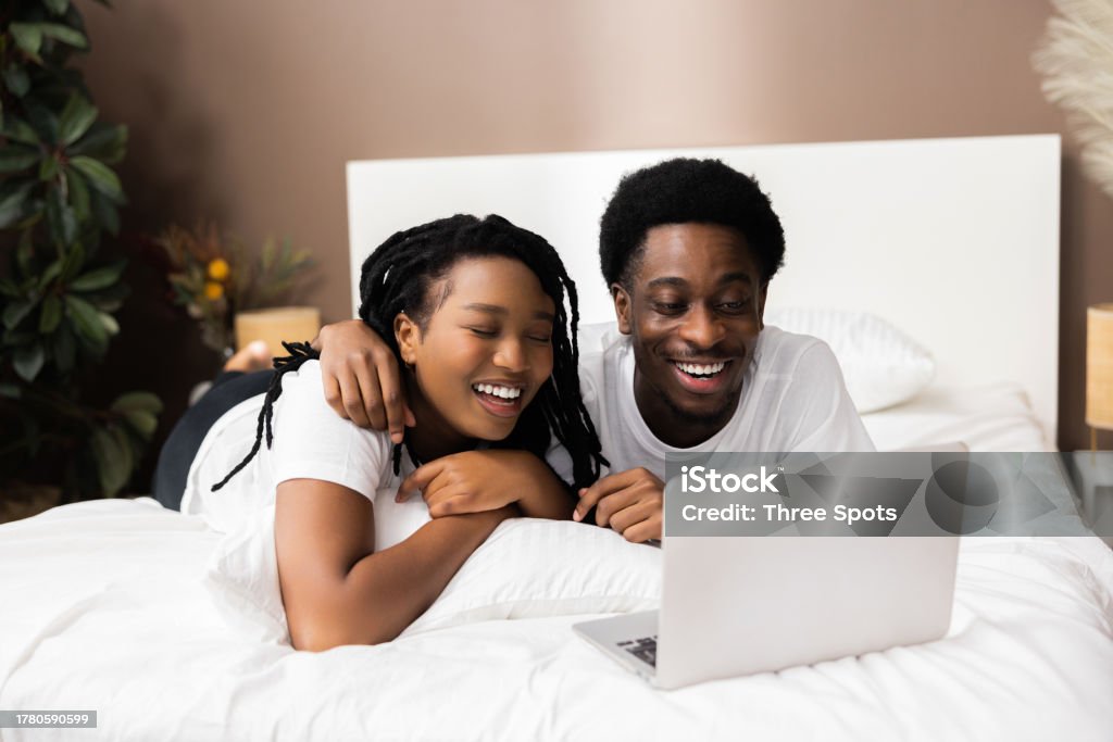 Young African American Black Couple Lying On Bed In Front Of Laptop