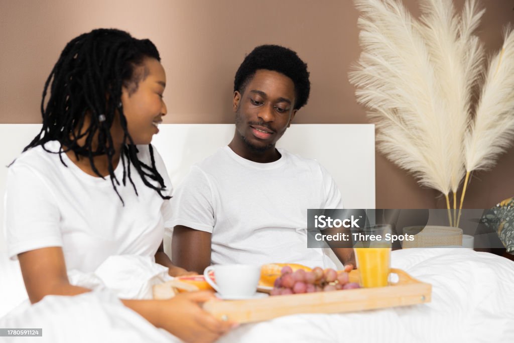 Happy Delighted African American Black Couple Lying In Bed Holding Tray