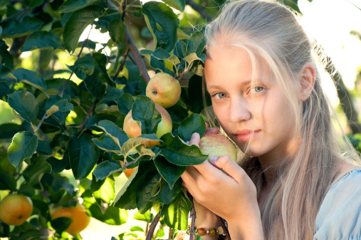 Outdoor Portrait Of Beautiful Blonde Girl Posing Near Apple Tree Stock
