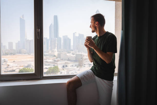 Free Stock Photo of Man Sitting on Window Sill Looking Out at City ...