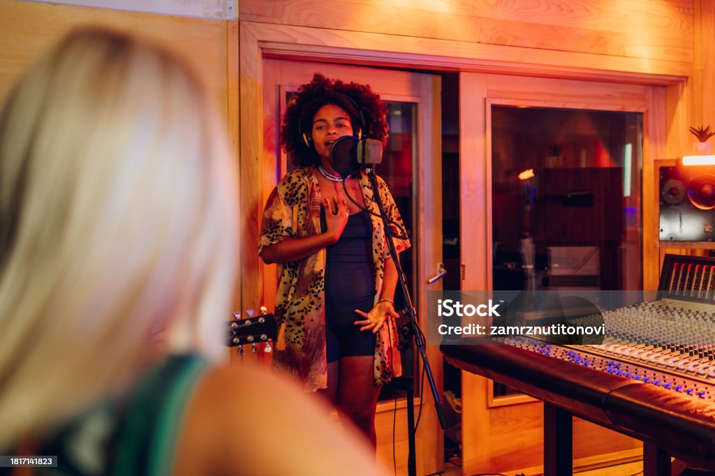 Young Multiracial Vocalist Singing Into A Recording Microphone In A