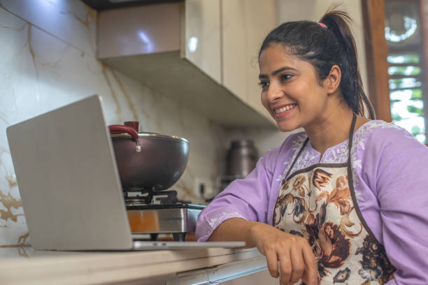 Free Stock Photo of Woman cooking in kitchen and having video call on ...