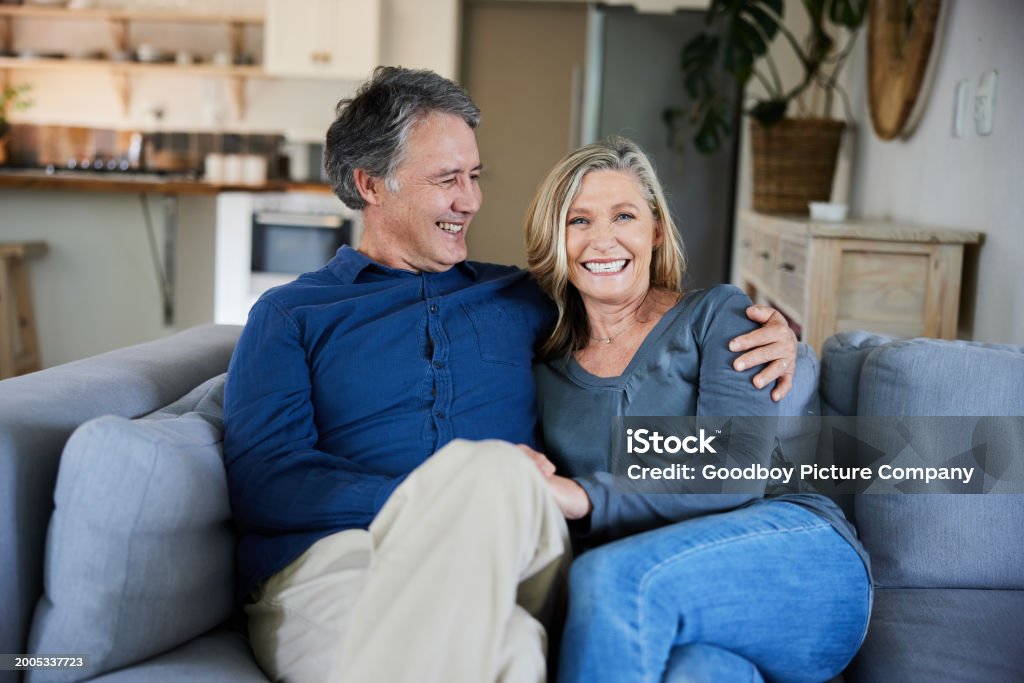 Smiling Mature Couple Relaxing Together On Their Sofa At Home Stock
