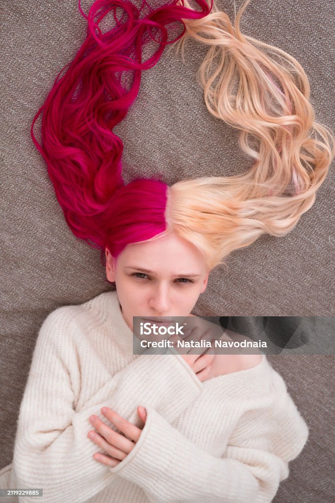 Young Blond Girl With Long Pink Colored Hair Laying On Bed At Home