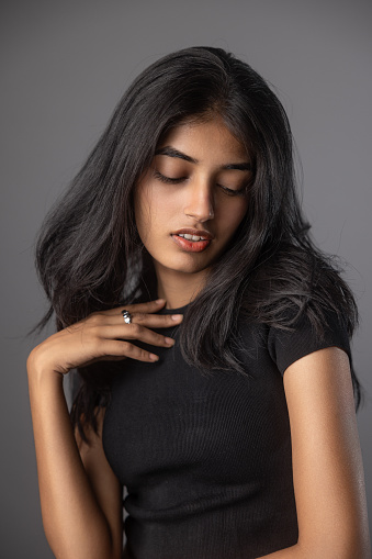 Young Indian Girl Posing Standing In Front Of A Grey Background Stock