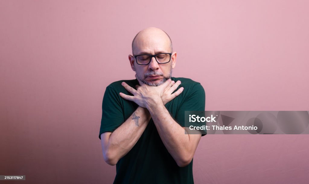 Bearded Bald Man With Prescription Glasses Squeezing His Neck With Both