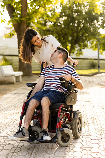 A Young Woman Cares For Her Disabled Brother In An Automatic Wheelchair