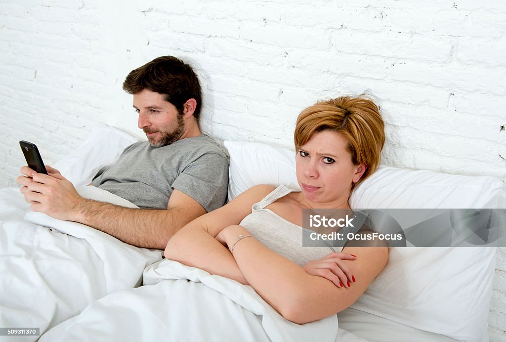 Couple In Bed Unsatisfied Wife Addict Husband Using Mobile Phone Stock